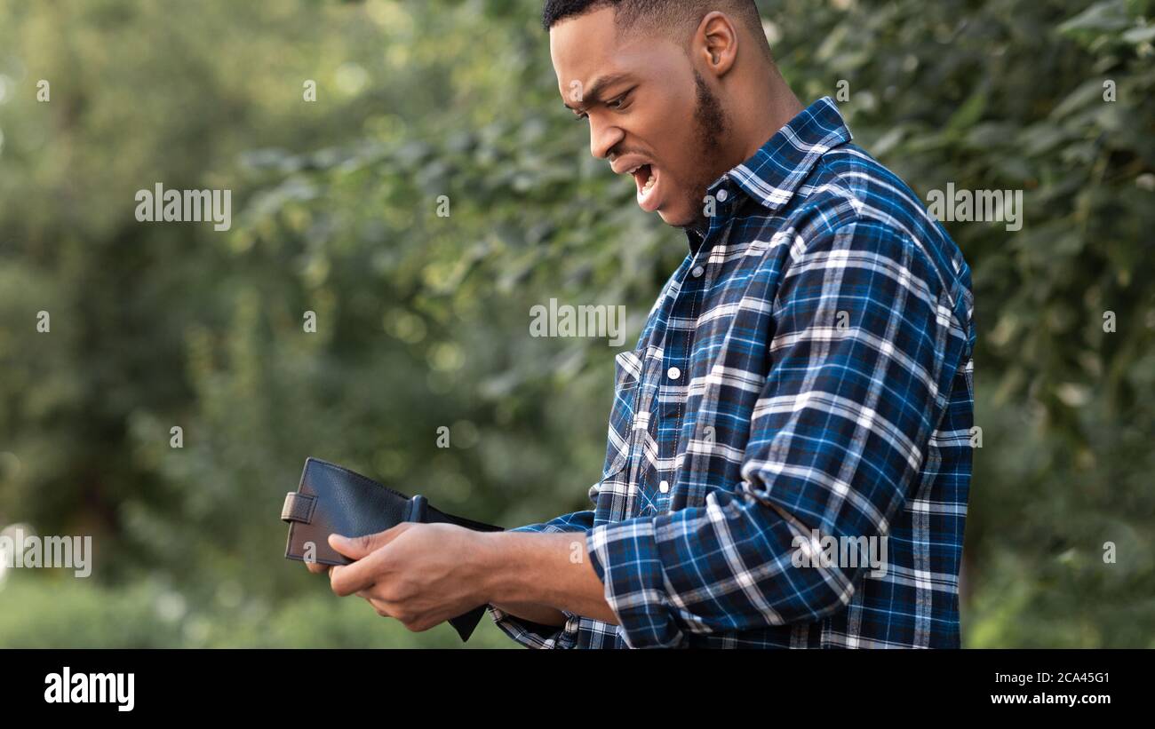 Speechless black guy looking at his empty purse Stock Photo - Alamy
