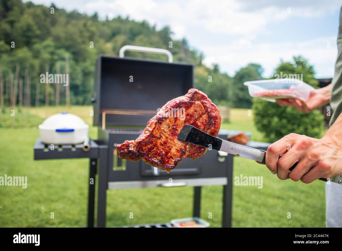 Home barbecue with charcoal in the backyard grilling steaks and other ...