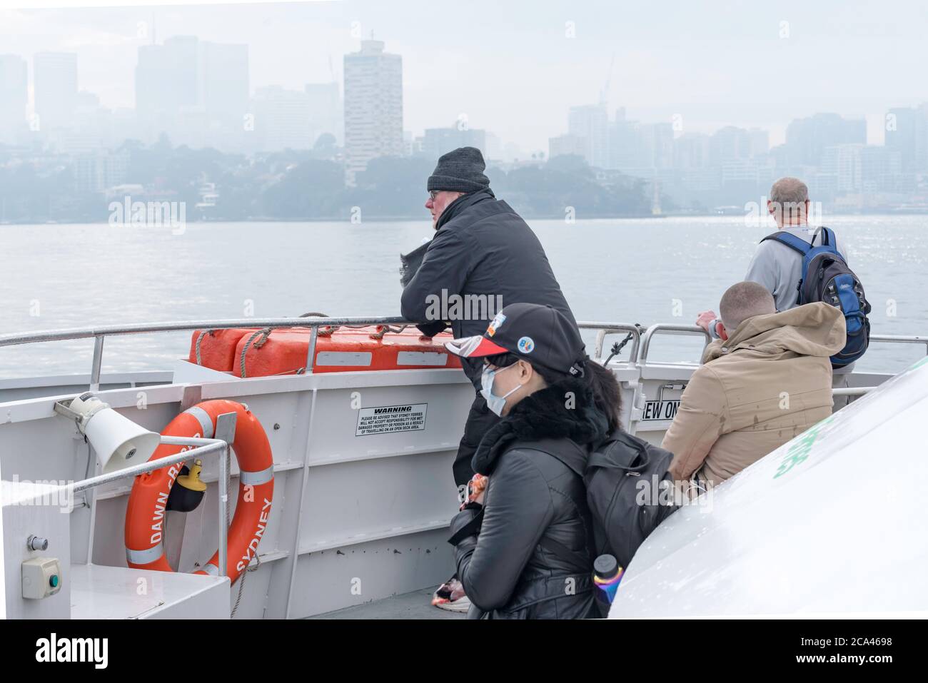 An Asian woman wearing a mask and other people not while riding on the ...