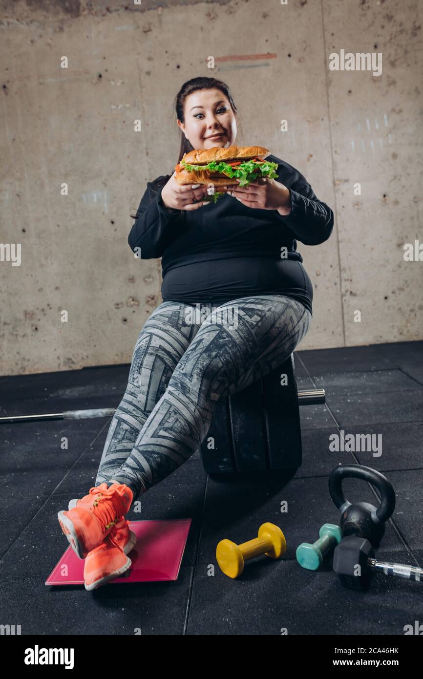 weak woman is crazy about fast food. full length photo. weak-willed ...