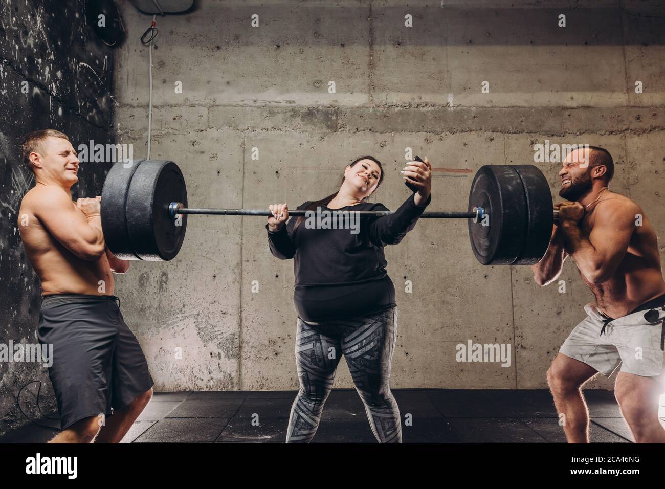 pleasant obese girl having fun with bodybuilders. joke, entertainment ...
