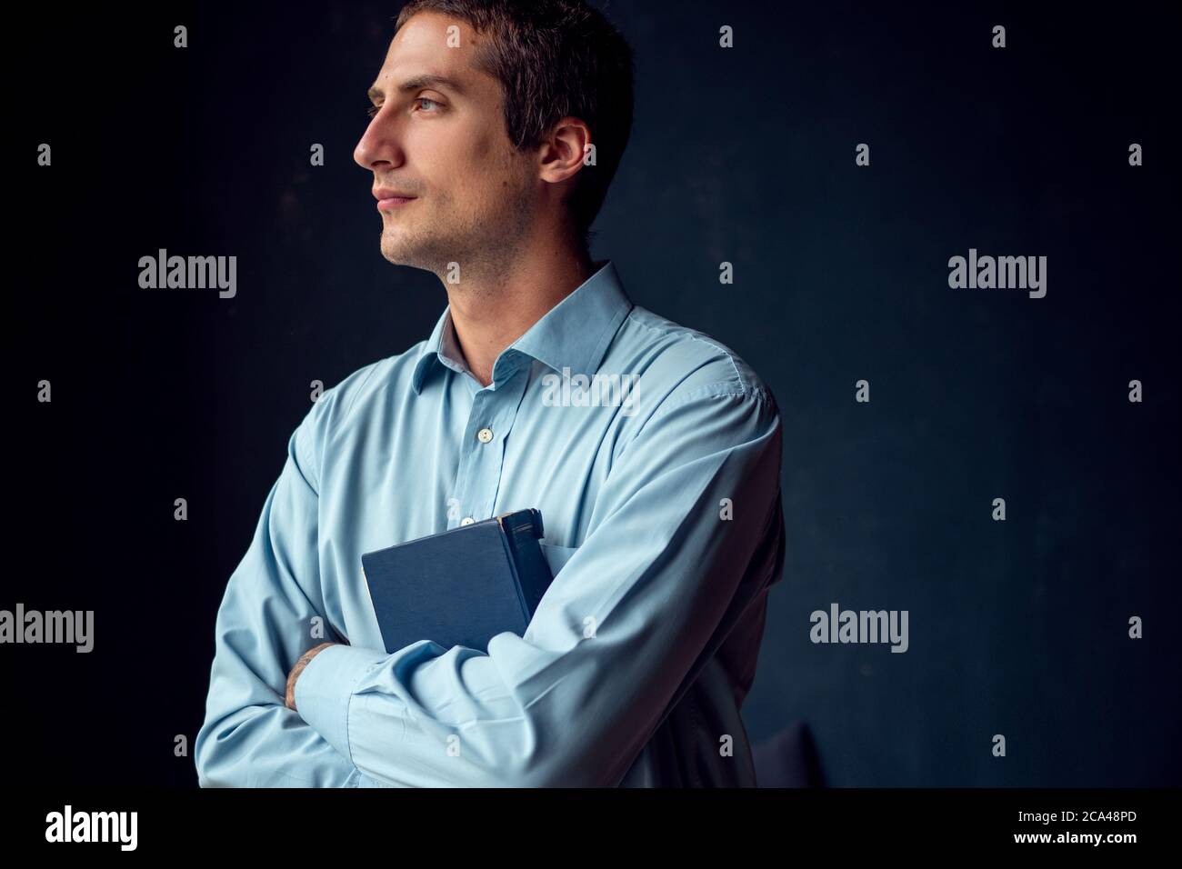 Young man reading a book, a guy in a blue shirt on a dark blue ...