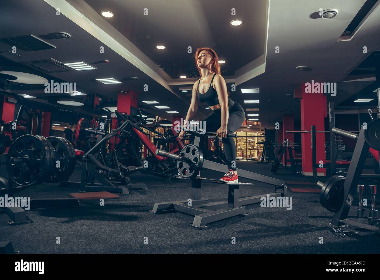 Heavy. Young muscular caucasian woman practicing in gym with equipment ...