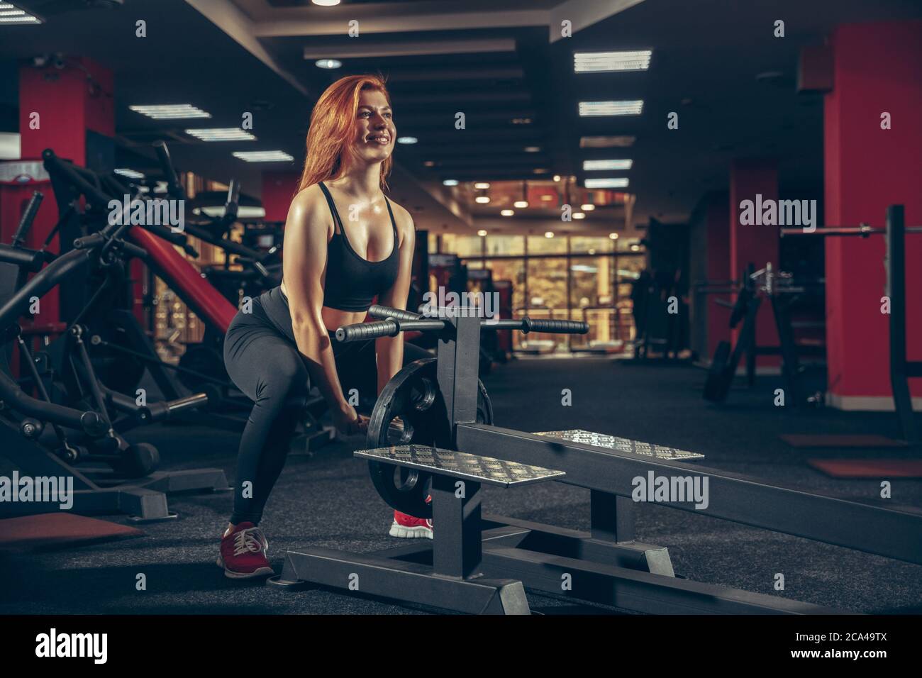 Heavy. Young muscular caucasian woman practicing in gym with equipment ...