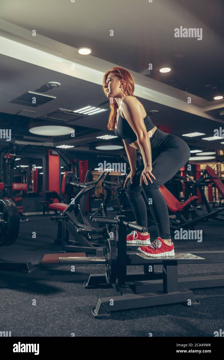 Heavy. Young muscular caucasian woman practicing in gym with equipment ...