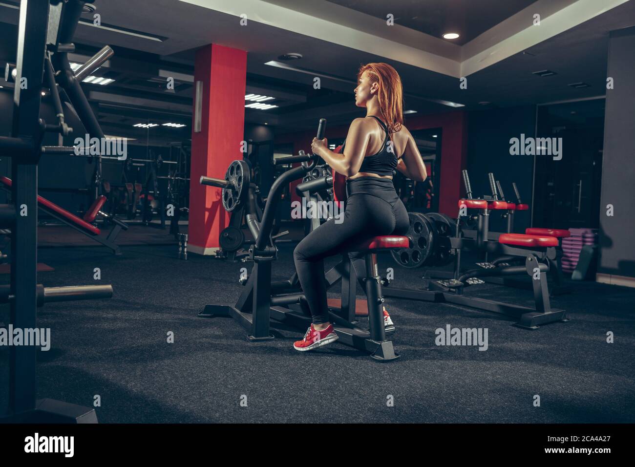 Heavy. Young muscular caucasian woman practicing in gym with equipment ...