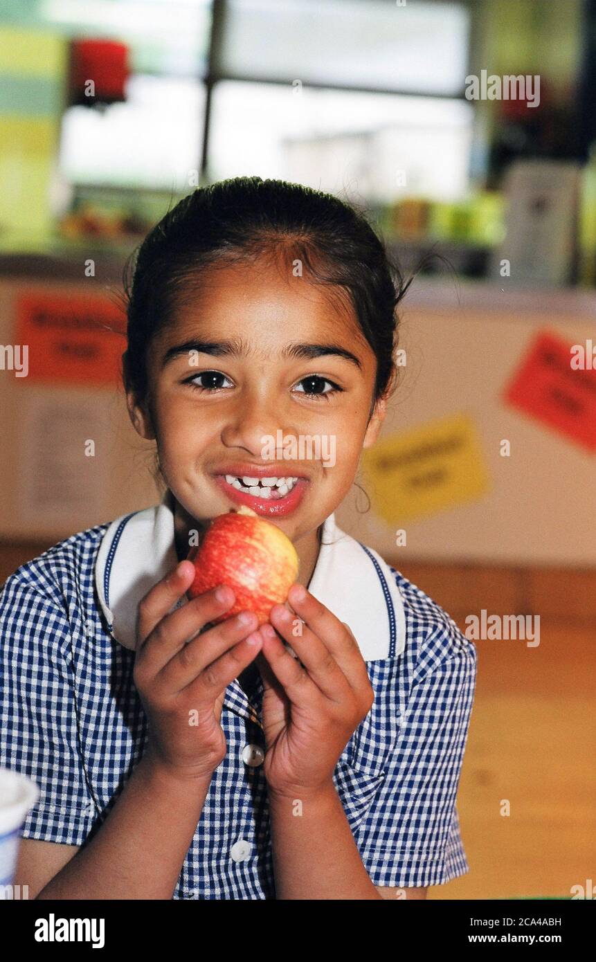 Schoolgirl eating an apple - fruit is given free to schoolchildren in ...