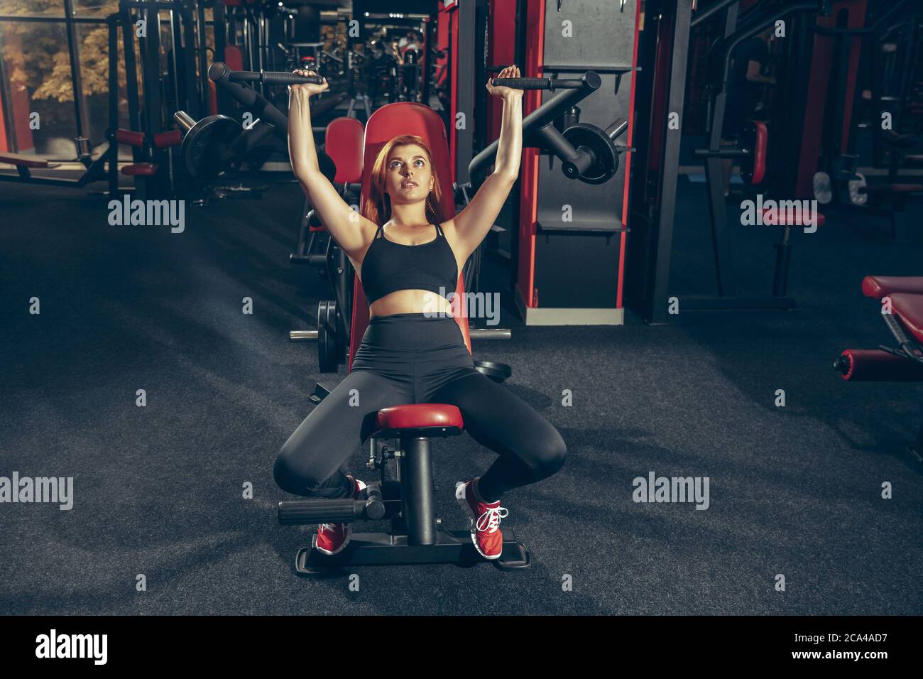 Heavy. Young muscular caucasian woman practicing in gym with equipment ...