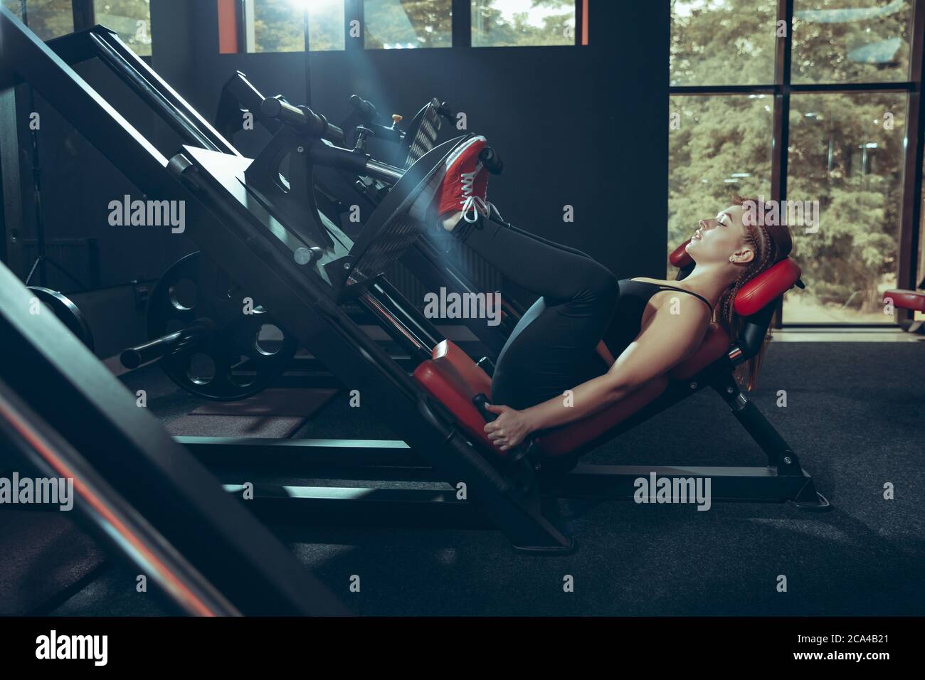 Hard. Young muscular caucasian woman practicing in gym with equipment ...