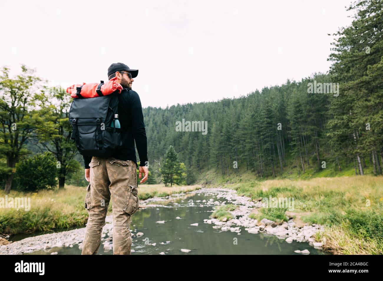 Young male nature explorer enjoying the view of the river in wilderness ...
