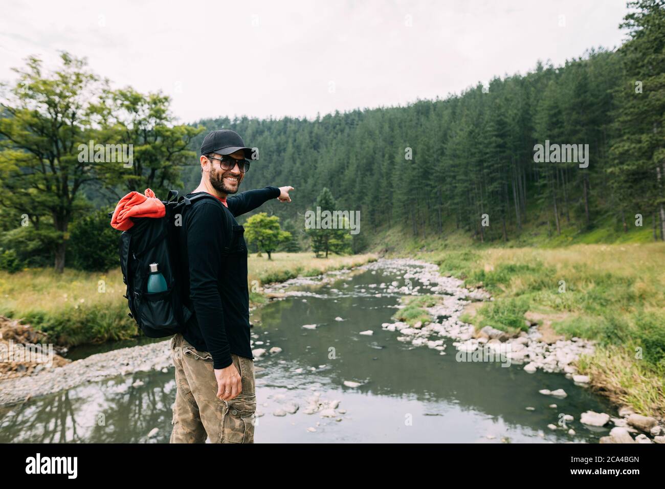 Young male nature explorer enjoying the view of the river in wilderness ...