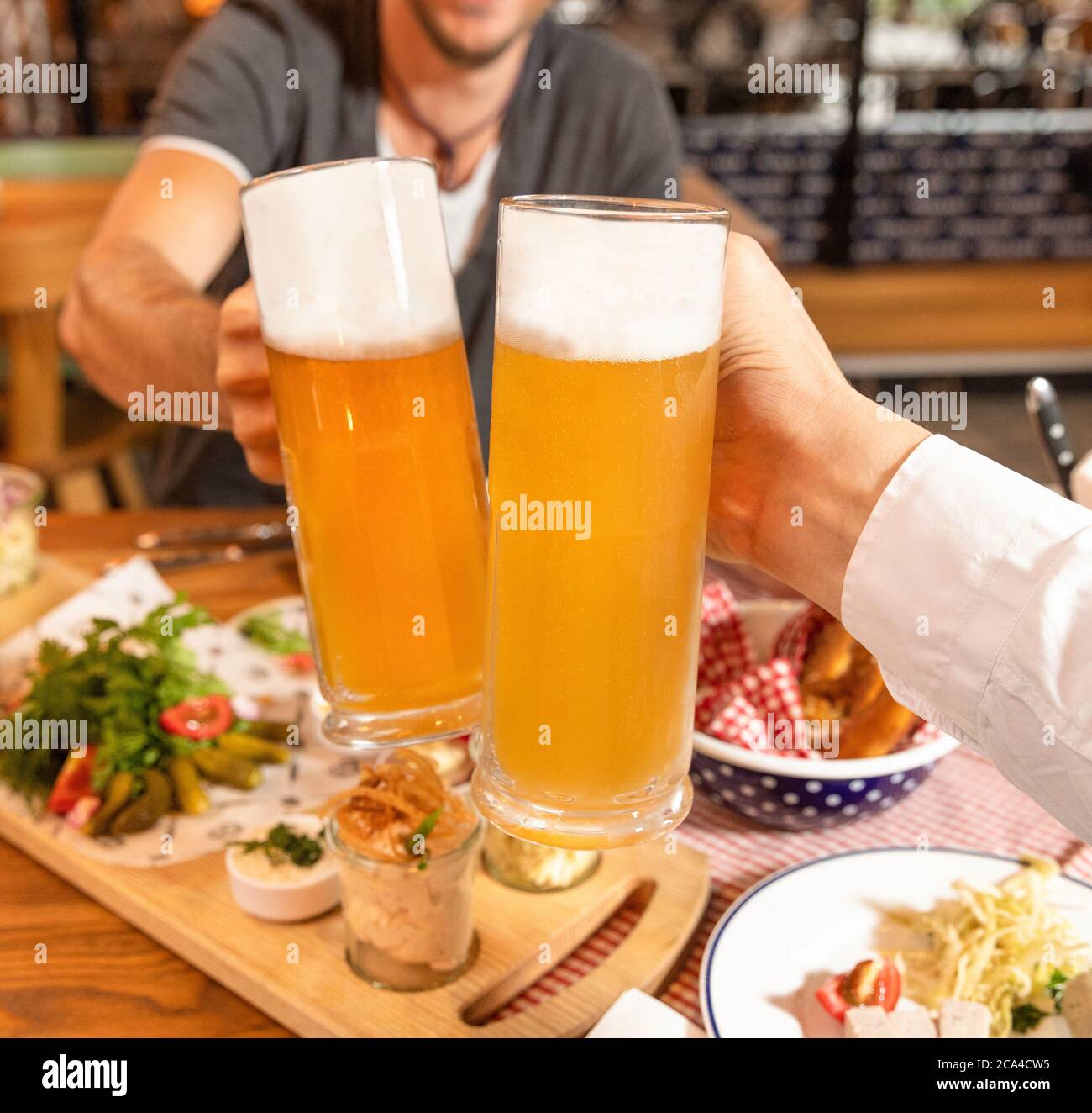 Clinking beer mugs close up, snacks on the table Stock Photo - Alamy