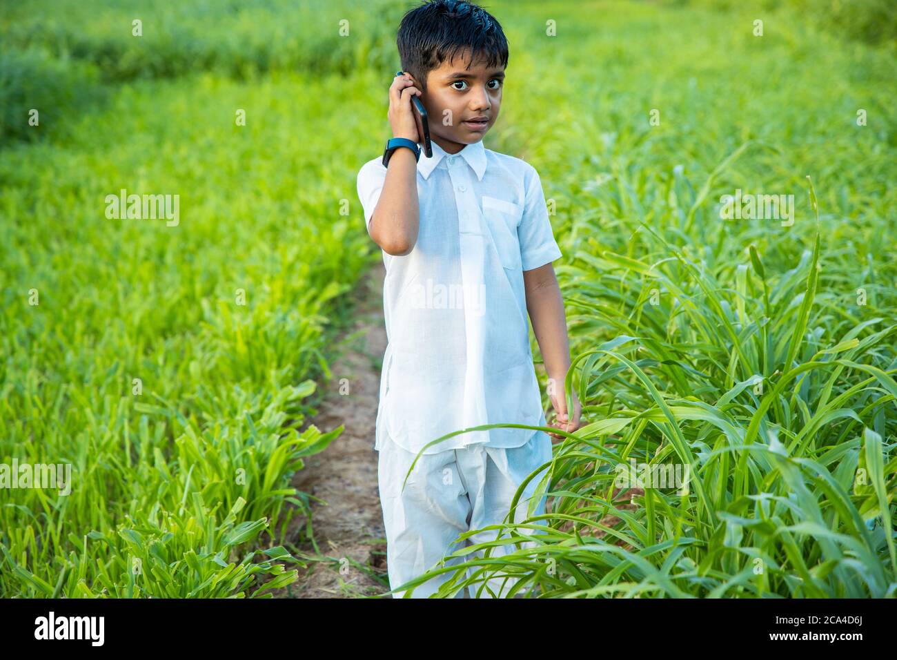 Portrait on cute indian child talking on mobile phone standing in ...