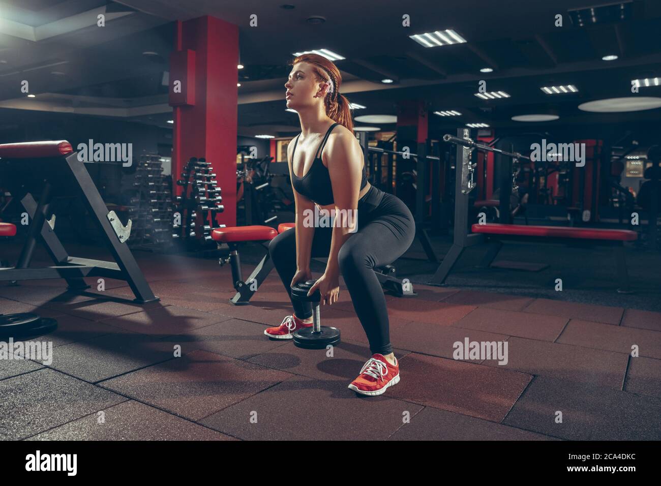 Sit up. Young muscular caucasian woman practicing in gym with equipment ...