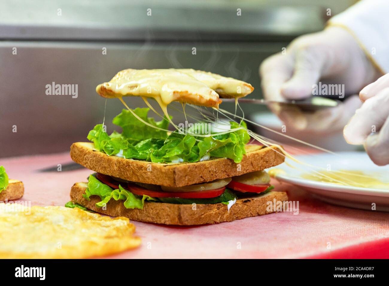 Chef in restaurant kitchen making cheesy club sandwich Stock Photo - Alamy