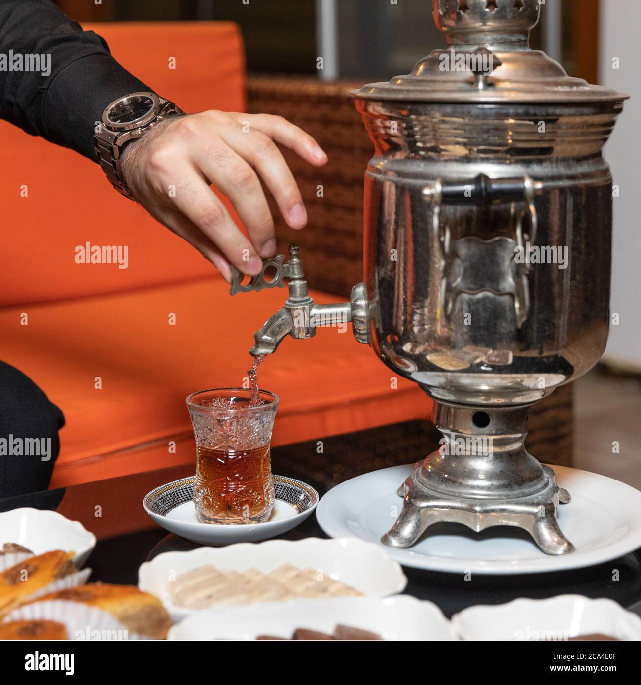 Man pouring tea from teapot at cafe Stock Photo - Alamy