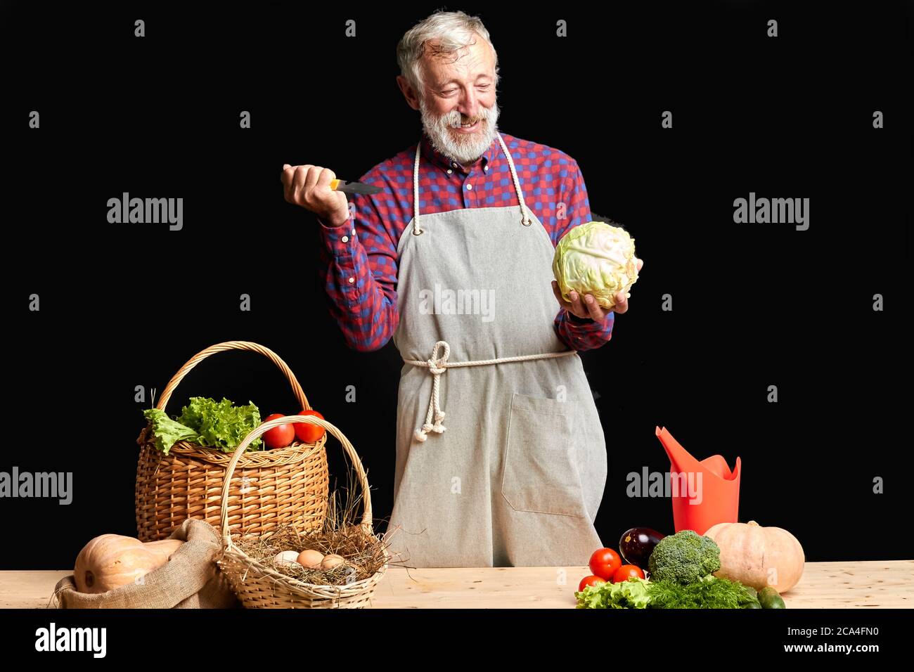 Cheerful senior male farmer having fun during cooking healthy lunch for ...