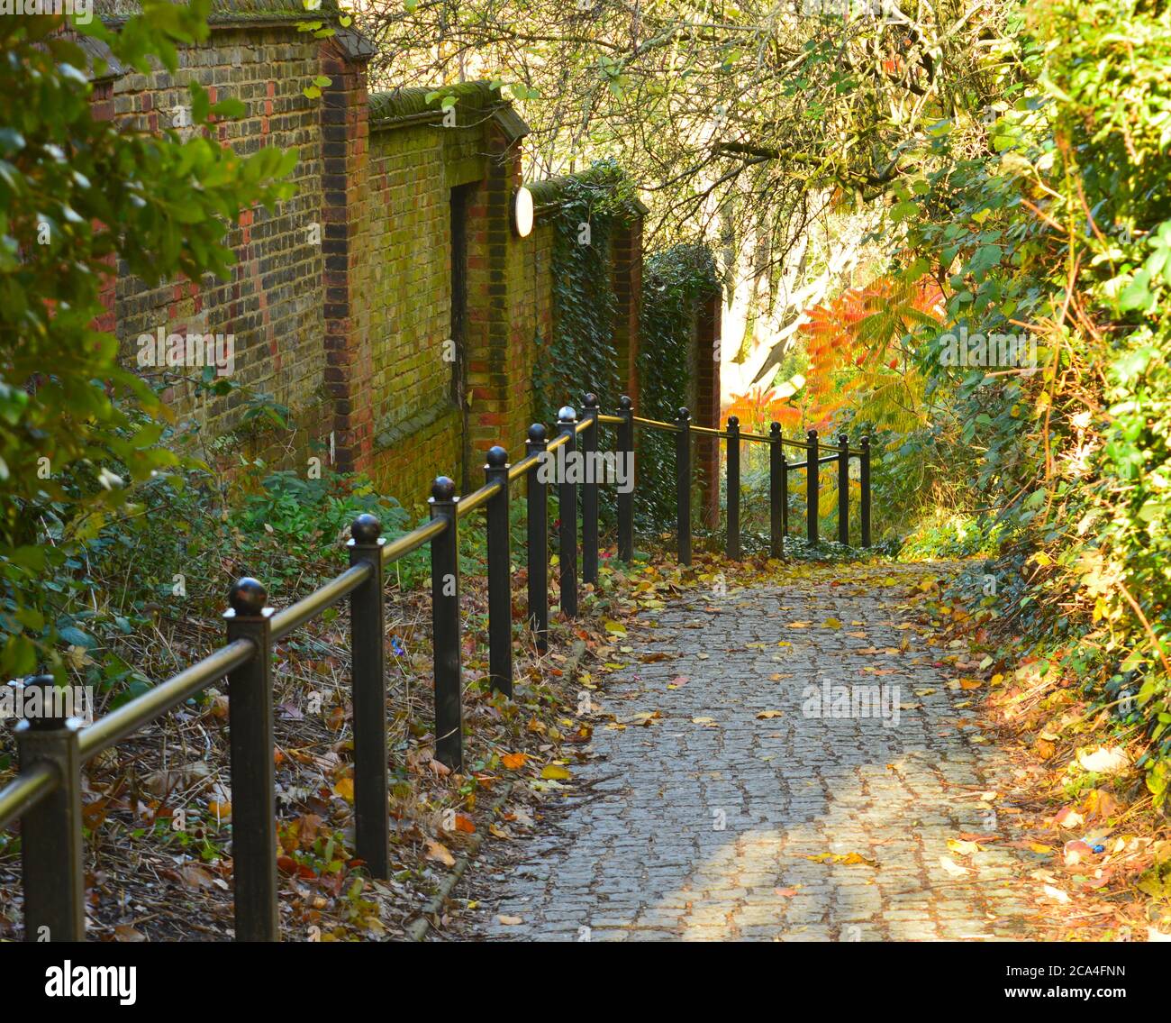 paved pathway with metal rail and brick wall on one side Stock Photo ...