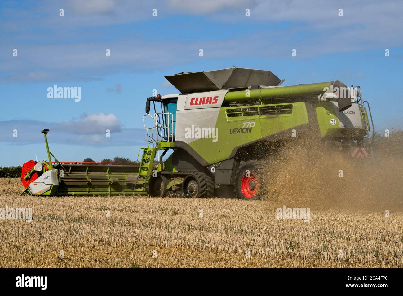 Winter Harvest Close side view of combined harvester at work in field ...