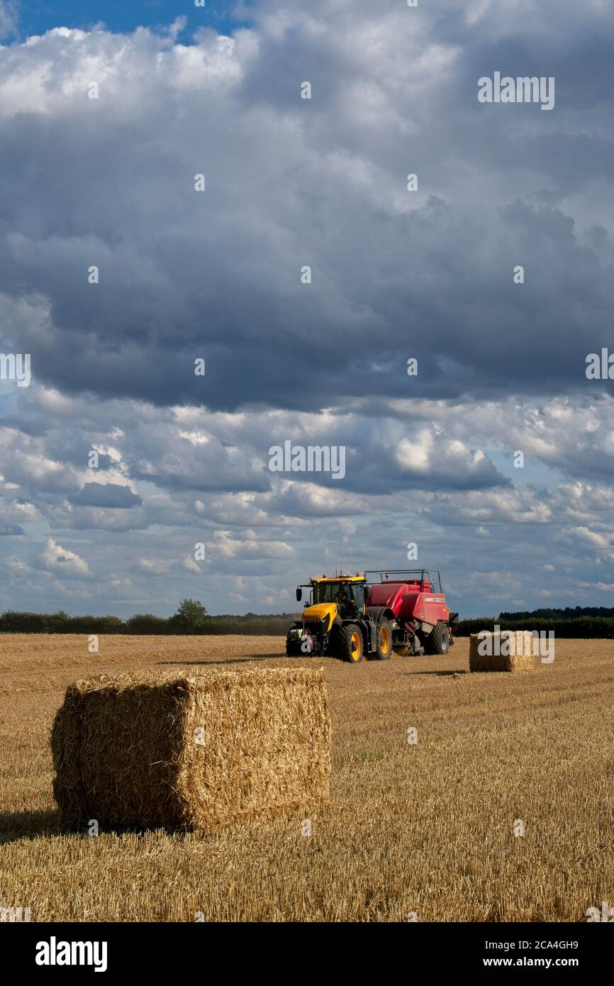 Baling after harvest Tractor towing bailer ejecting bale onto the ...