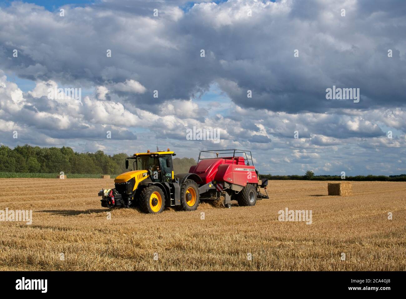 Baling after harvest Tractor towing bailer ejecting bale onto the ...