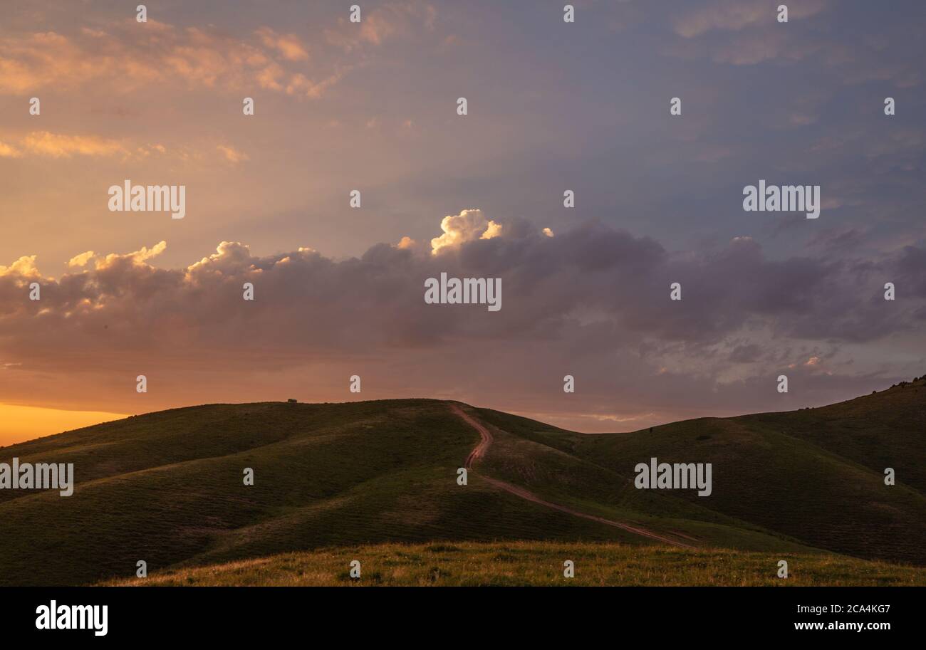 A large green grass mountain in the background and clouds Stock Photo ...