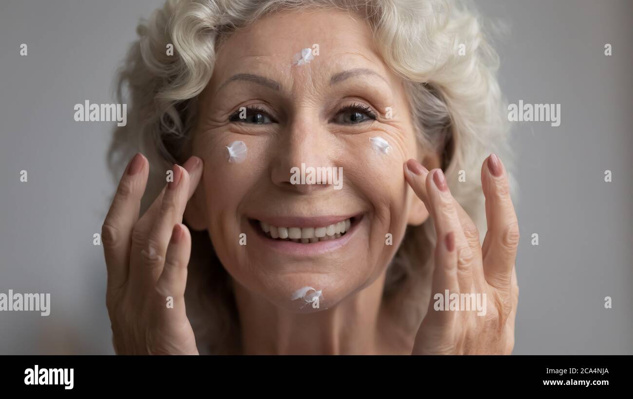 Closeup senior woman applying effective facial cream feels happy Stock ...