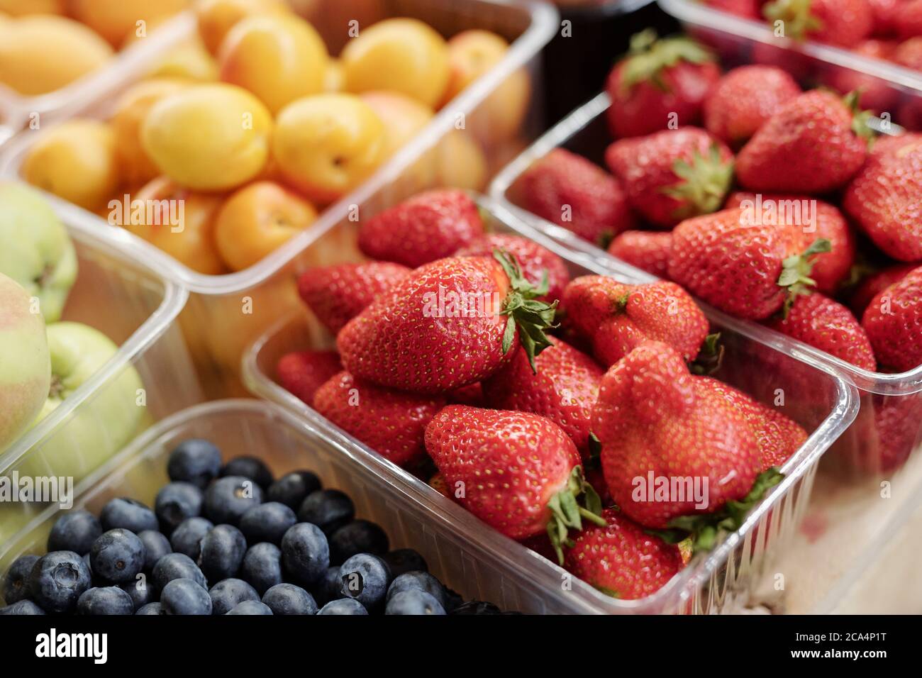 Close-up of fresh fruits and berries in plastic containers placed on ...
