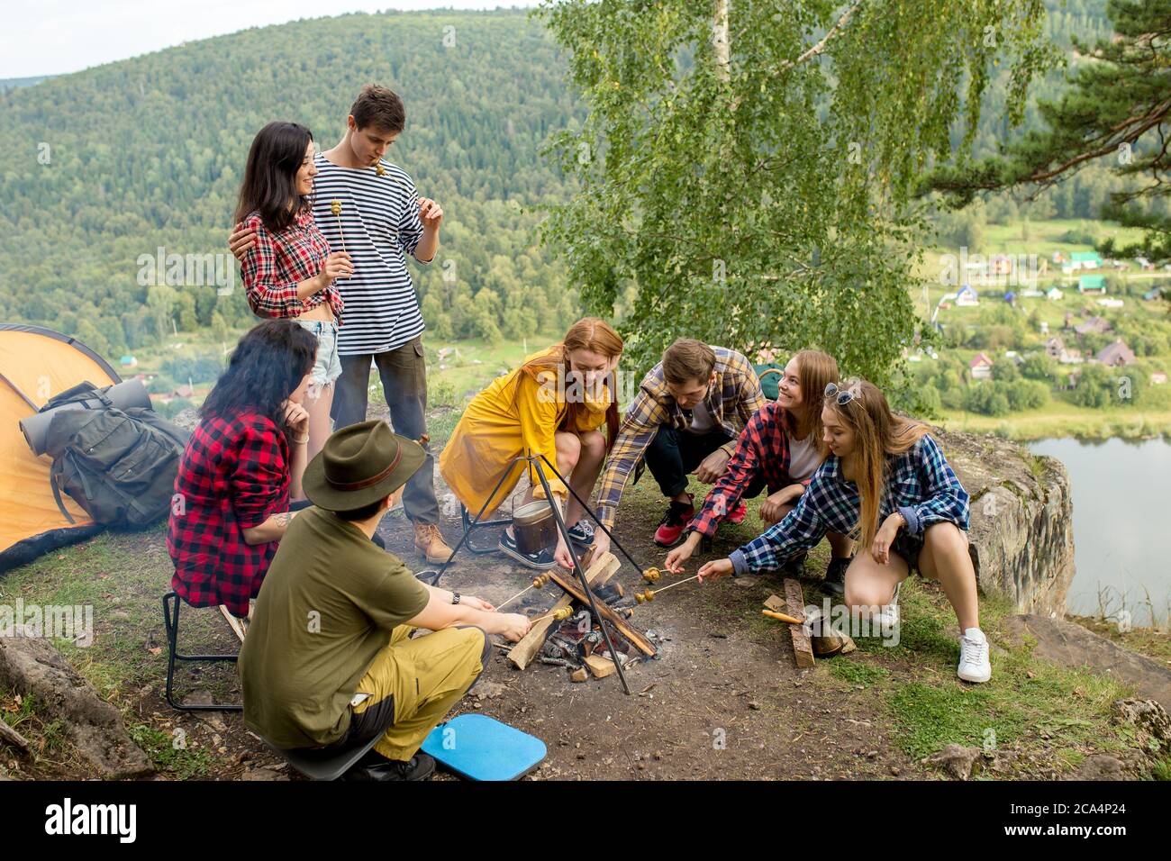 a group of young people cooking supper outdoors while resting on the ...
