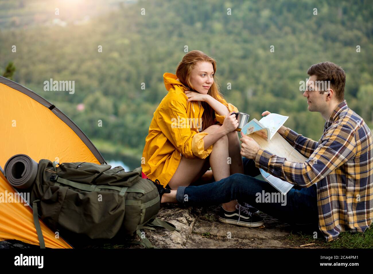 Happy romantic couple going on a hike, planning their route, side view ...