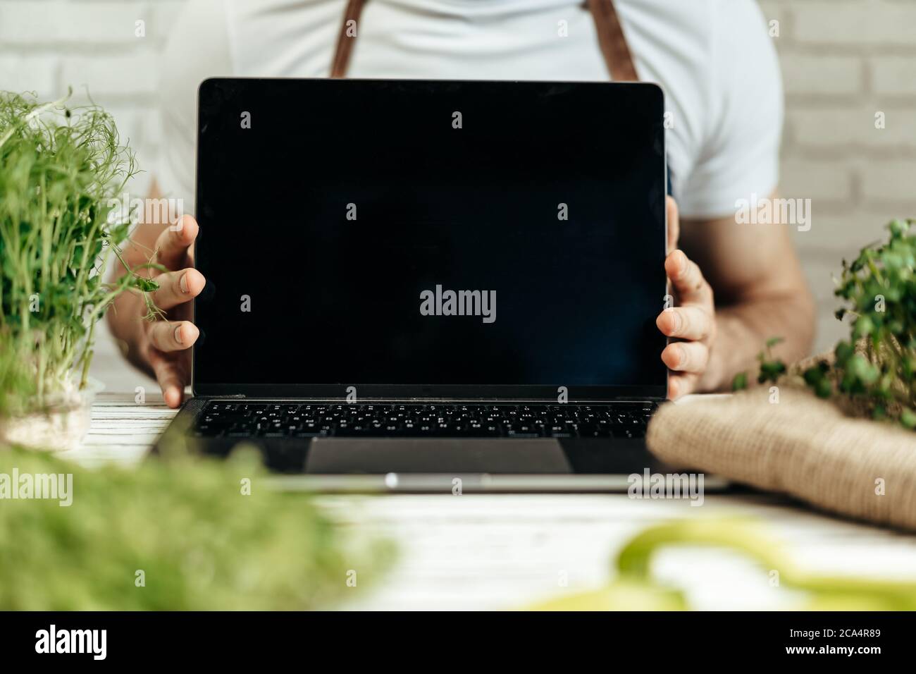 Man farmer shows black screen of laptop and sits at the table with ...