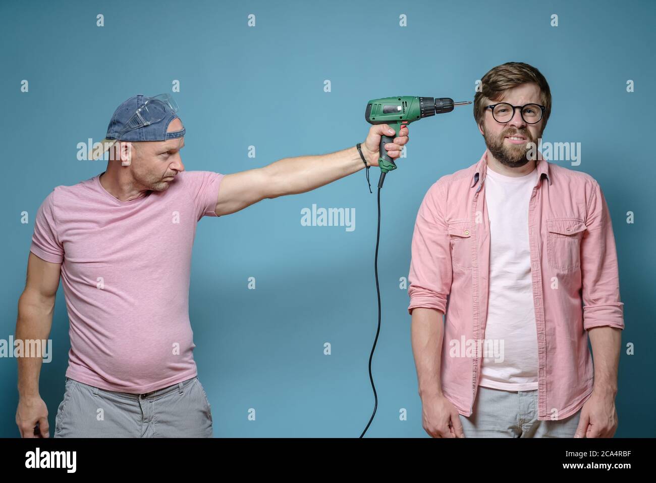 Serious man put an electric screwdriver to the unfortunate male head ...