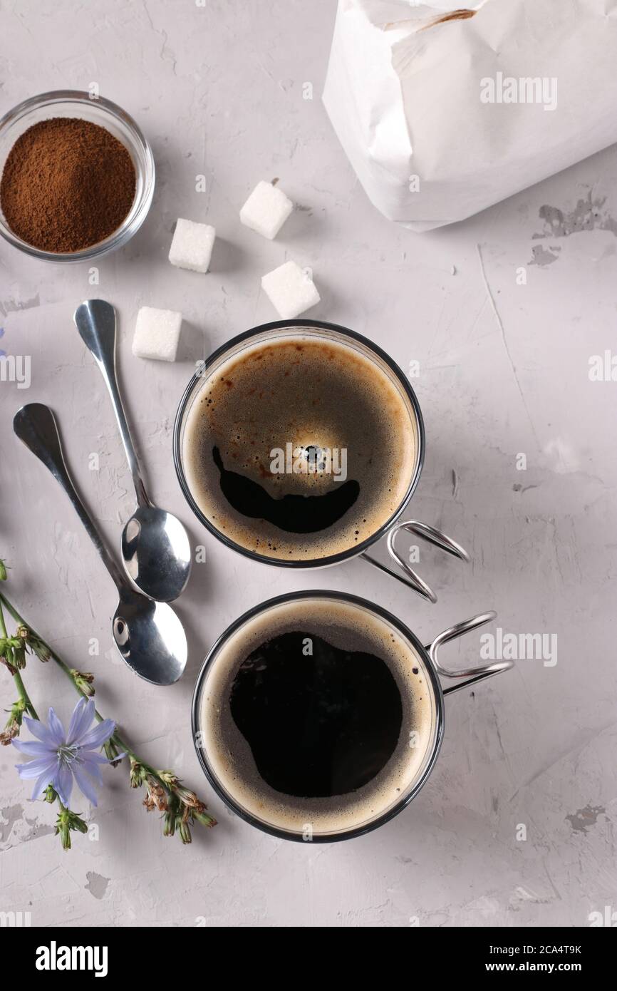 Chicory beverage in two glass cups, with concentrate and flowers on ...