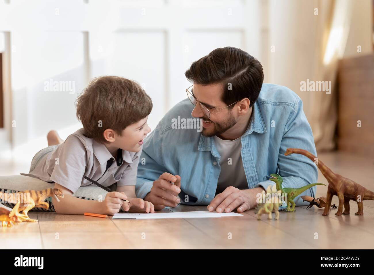 Emotional positive father involved in funny domestic activity with son ...