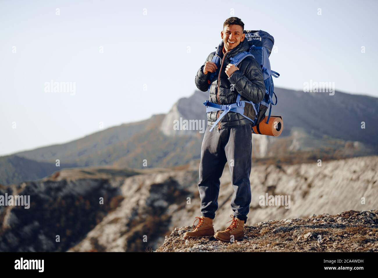 Male backpacker in hiking equipment standing at the top of the mountain ...