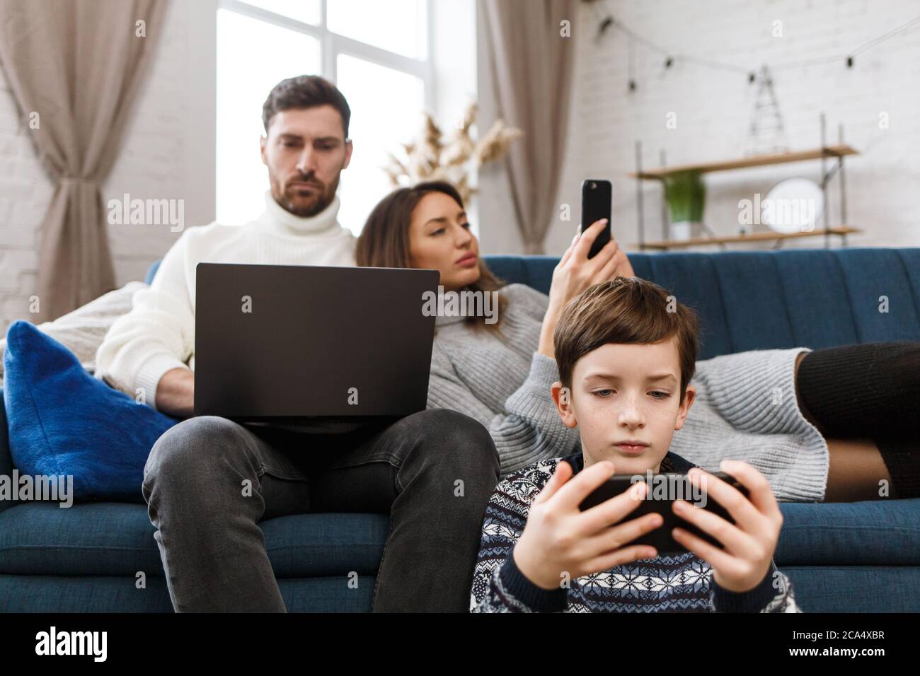 Mother, father and son using laptop and mobile phones at home. Family ...