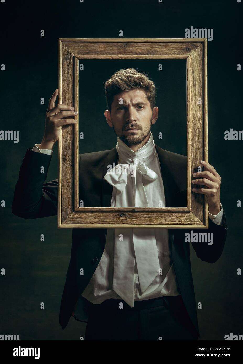 Out of time. Young man in suit as Dorian Gray isolated on dark green ...