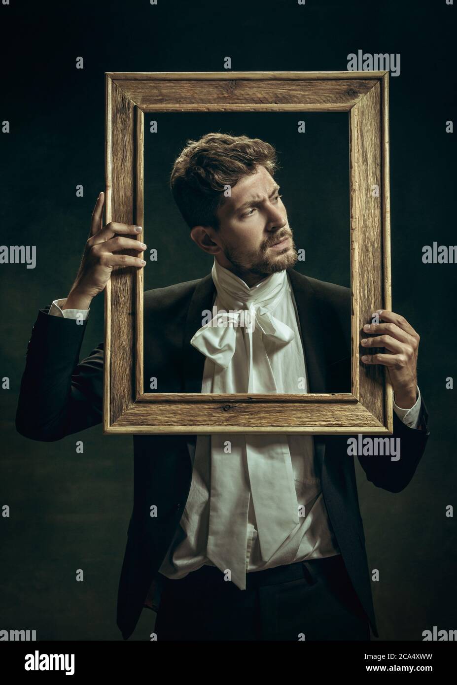 Out of time. Young man in suit as Dorian Gray isolated on dark green ...