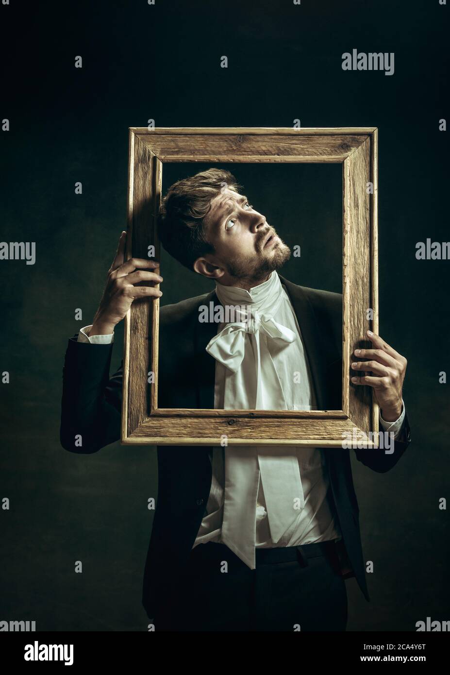 Portrait. Young man in suit as Dorian Gray isolated on dark green ...