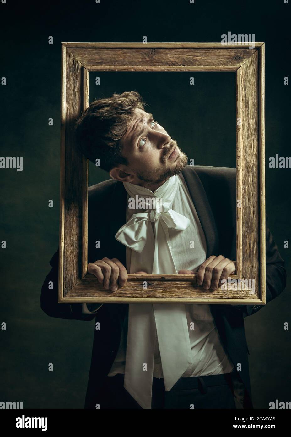 Soul portrait. Young man in suit as Dorian Gray isolated on dark green ...