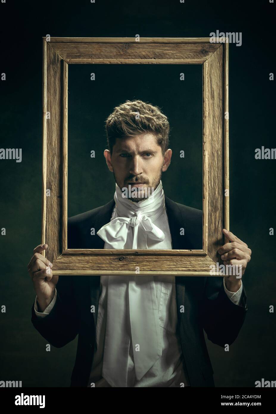 Soul portrait. Young man in suit as Dorian Gray isolated on dark green ...