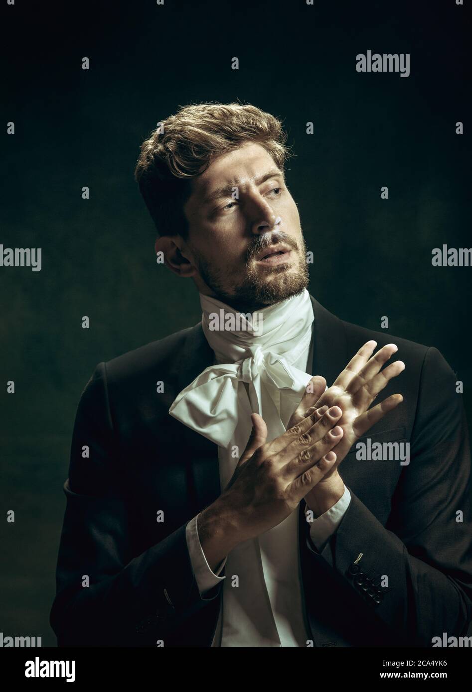 Opium. Young man in suit as Dorian Gray isolated on dark green ...