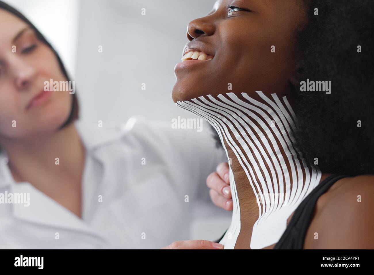 Kinesiology taping. Physiotherapist applying kinesiology tape to patient neck. Therapist ...