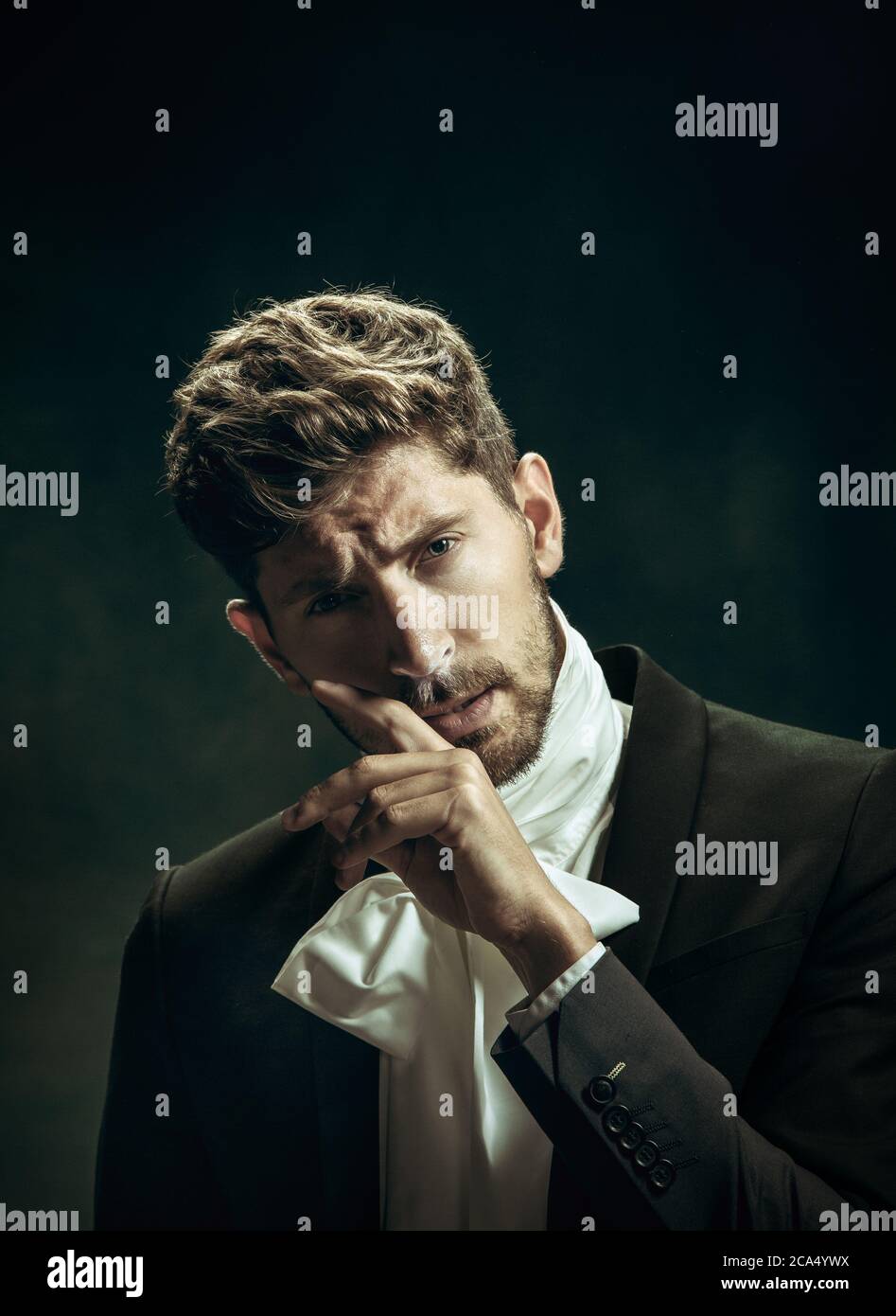 Sincere sin. Young man in suit as Dorian Gray isolated on dark green ...