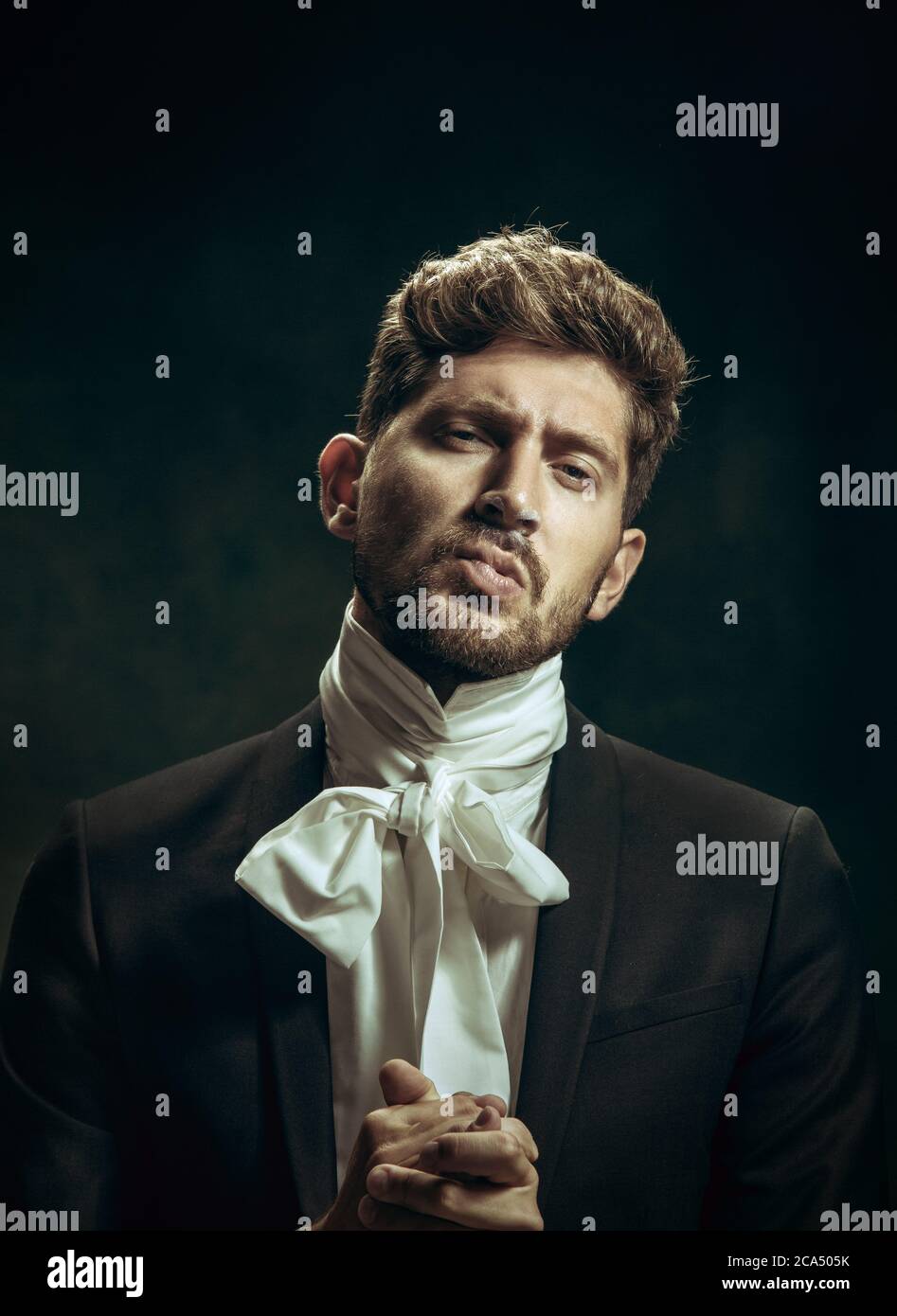 Sincere sin. Young man in suit as Dorian Gray isolated on dark green ...