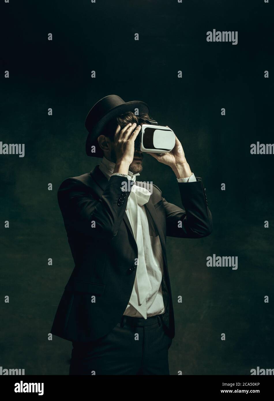 Playing VR. Young man in suit as Dorian Gray isolated on dark green ...