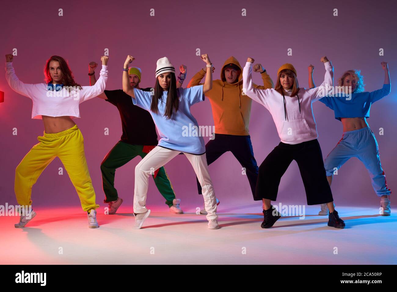 Group of energetic street dancers in sportswear, standing on brightly ...