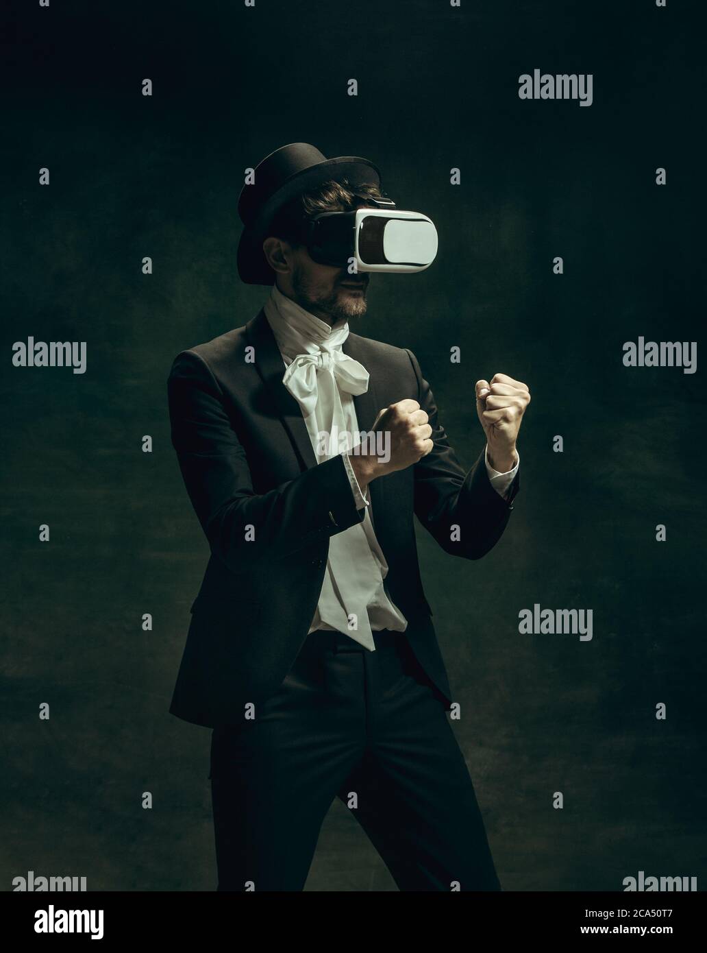 Playing VR. Young man in suit as Dorian Gray isolated on dark green ...