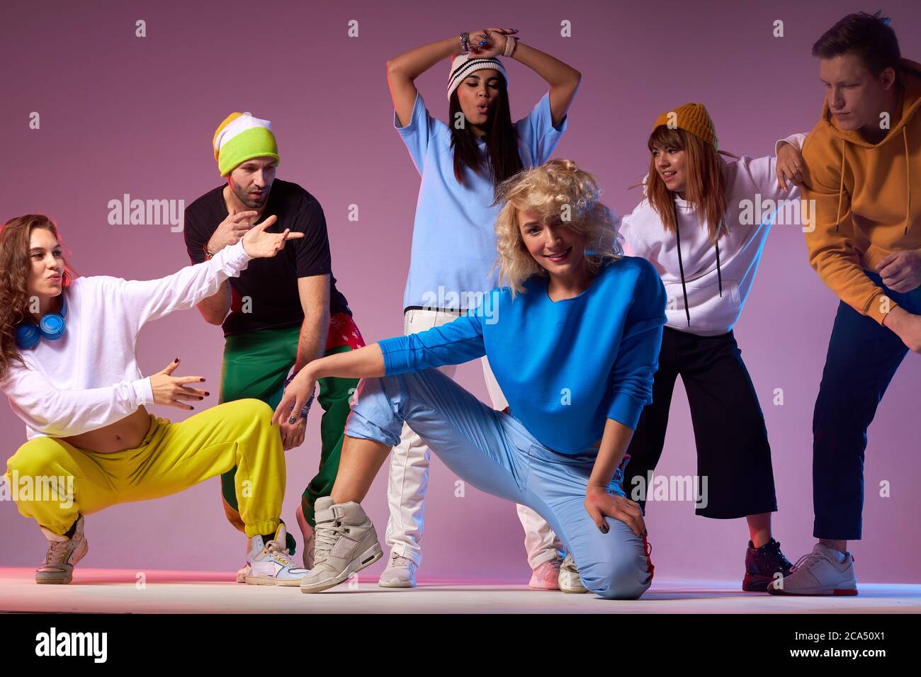 Playful cheerful group of people happily looking at female dancer ...