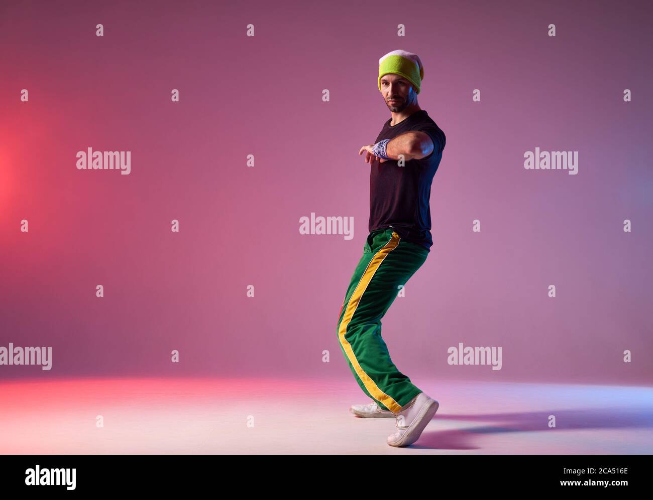 Modern breakdancer in sportive clothes, stretching elbow towards camera ...